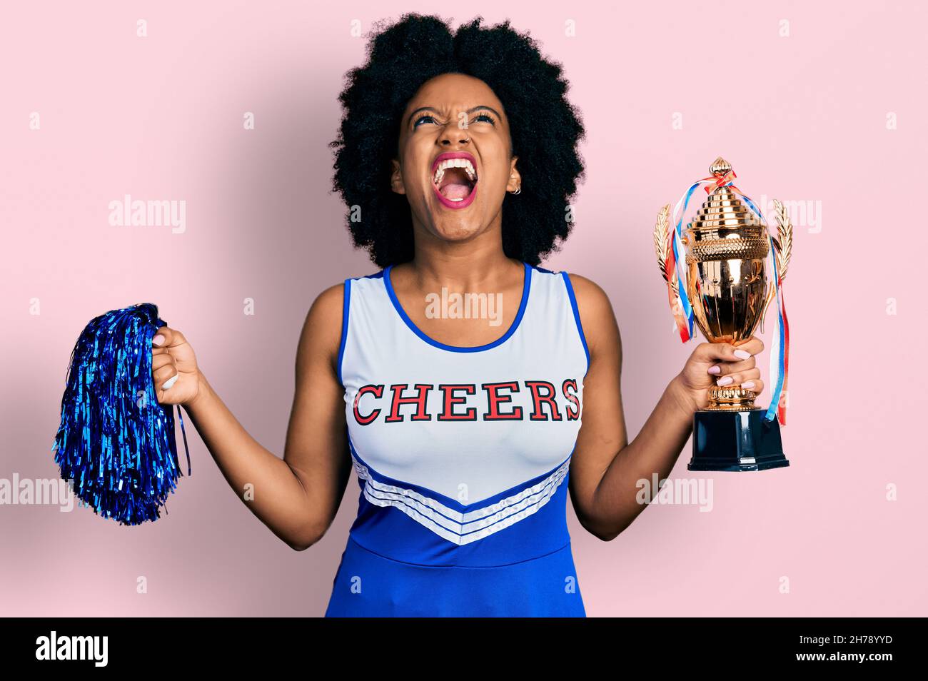 Young african american woman wearing cheerleader uniform holding pompom ...