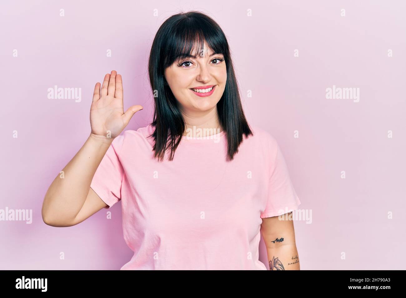Young hispanic woman wearing casual clothes waiving saying hello happy ...