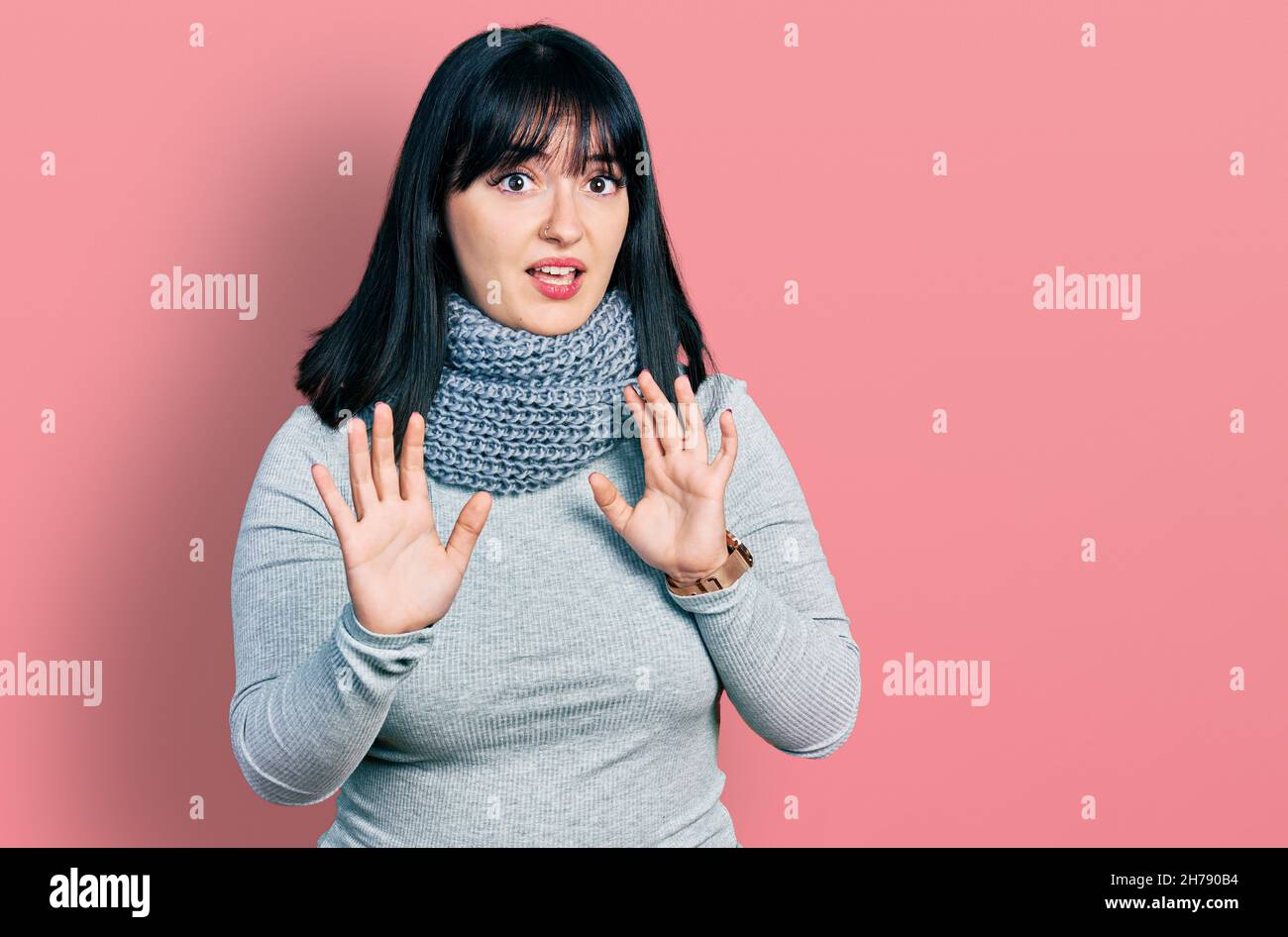 Young hispanic plus size woman wearing winter scarf afraid and ...