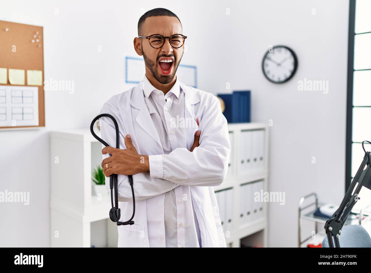 African american doctor man holding stethoscope at the clinic angry and ...