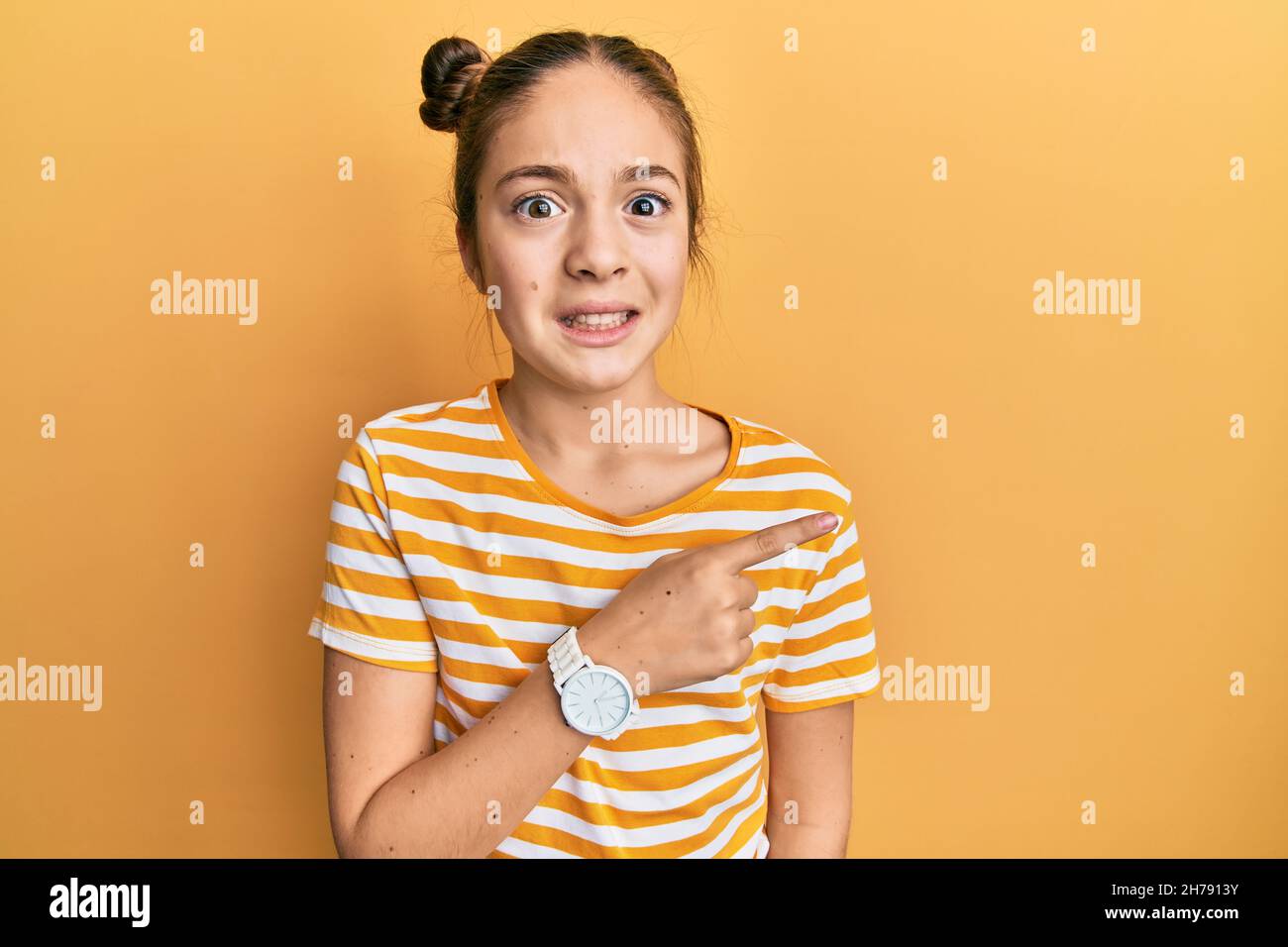 Beautiful brunette little girl wearing casual striped t shirt pointing ...