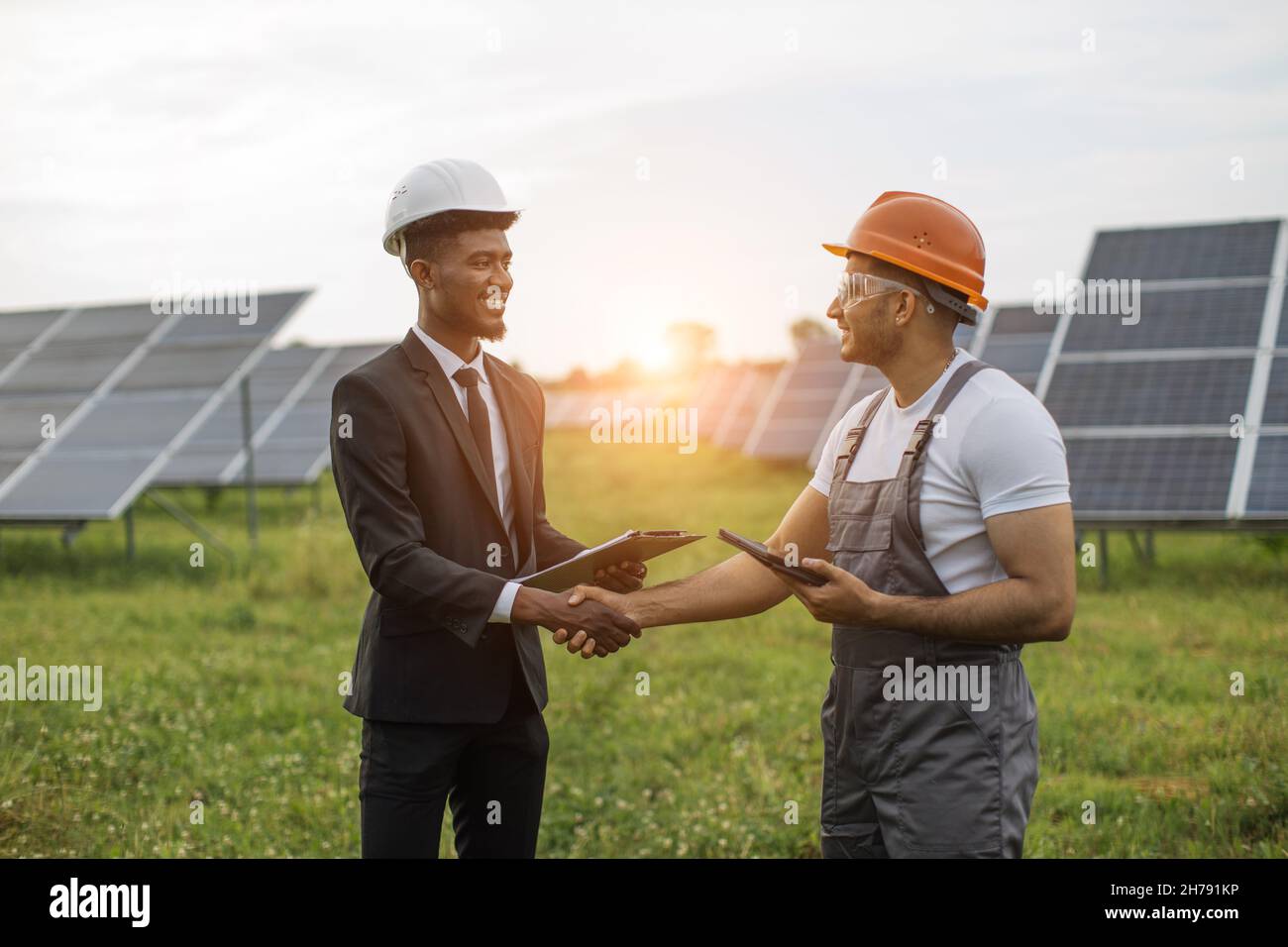 African american man in suit and white helmet shaking hands with indian ...
