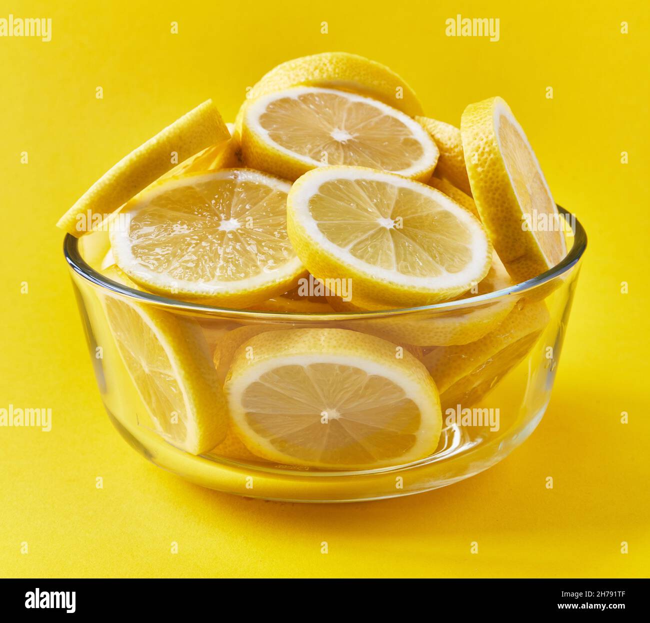 Bowl of slices of lemon on a yellow background Stock Photo - Alamy
