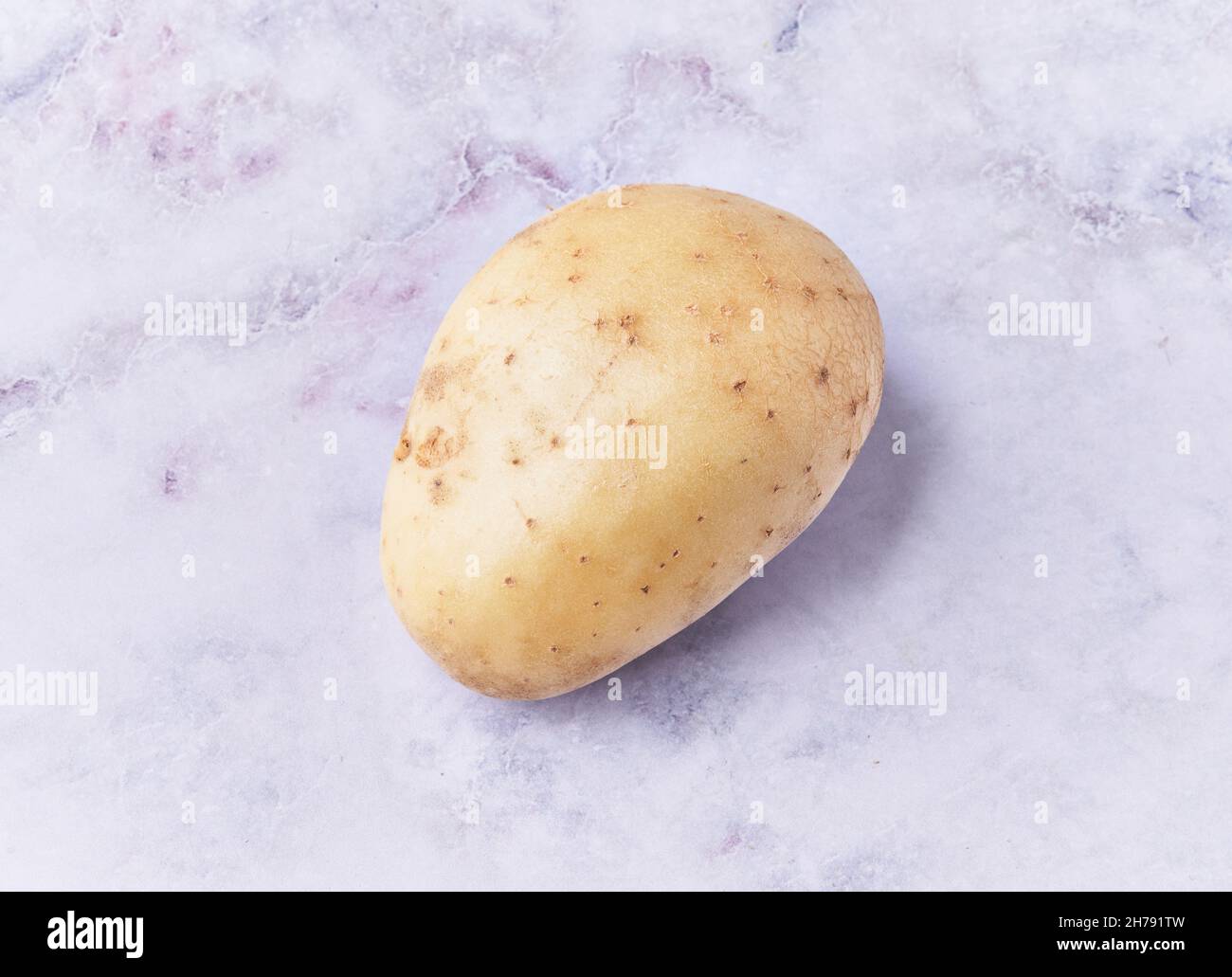 SIngle potato on a marble surface Stock Photo - Alamy