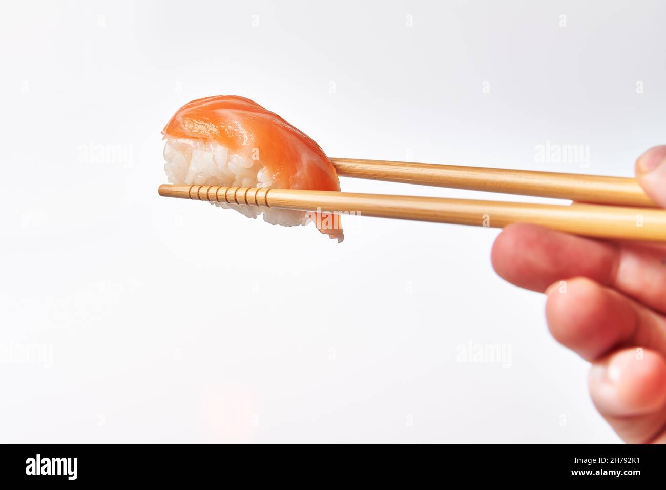 Chopsticks holding single salmon nigiri sushi isolated on white ...