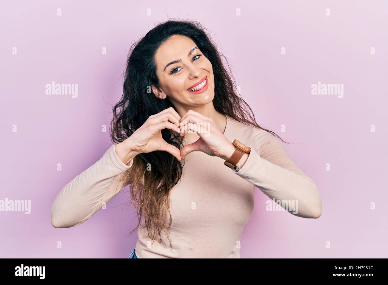 Young hispanic woman wearing casual clothes smiling in love doing heart ...