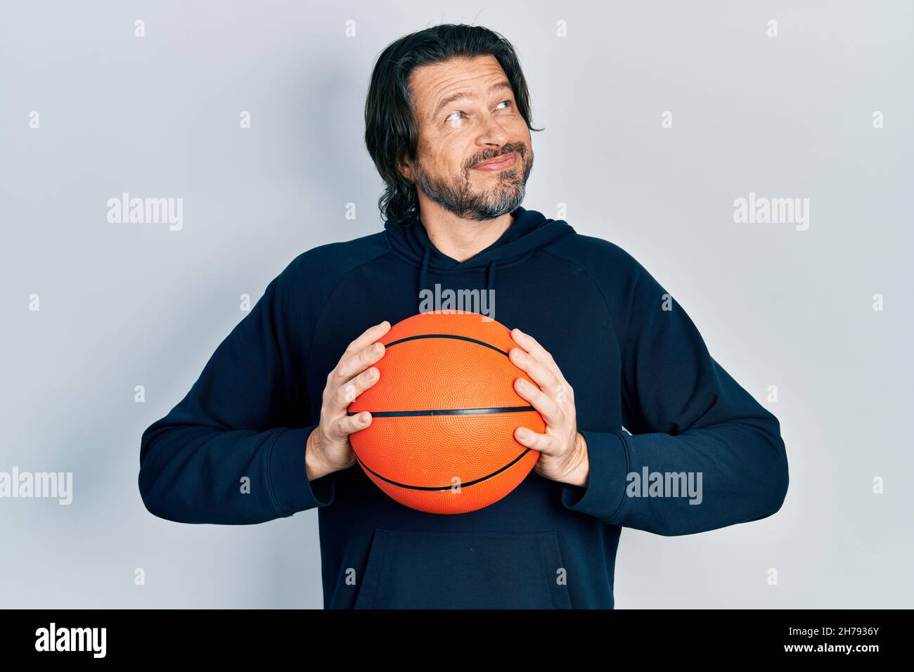 Middle age caucasian man holding basketball ball smiling looking to the ...