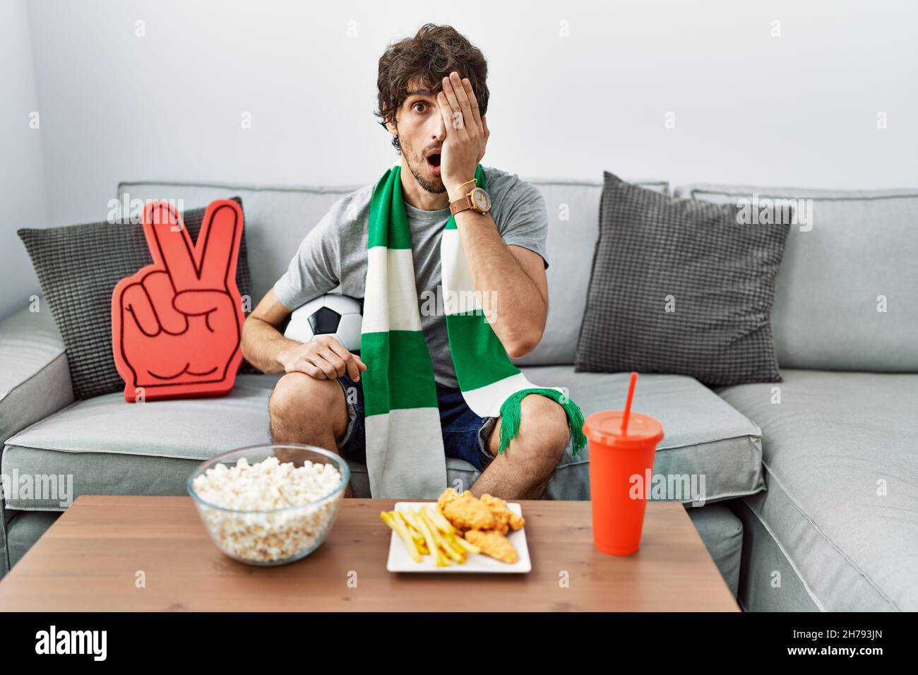 Young hispanic man football hooligan cheering game at home yawning ...