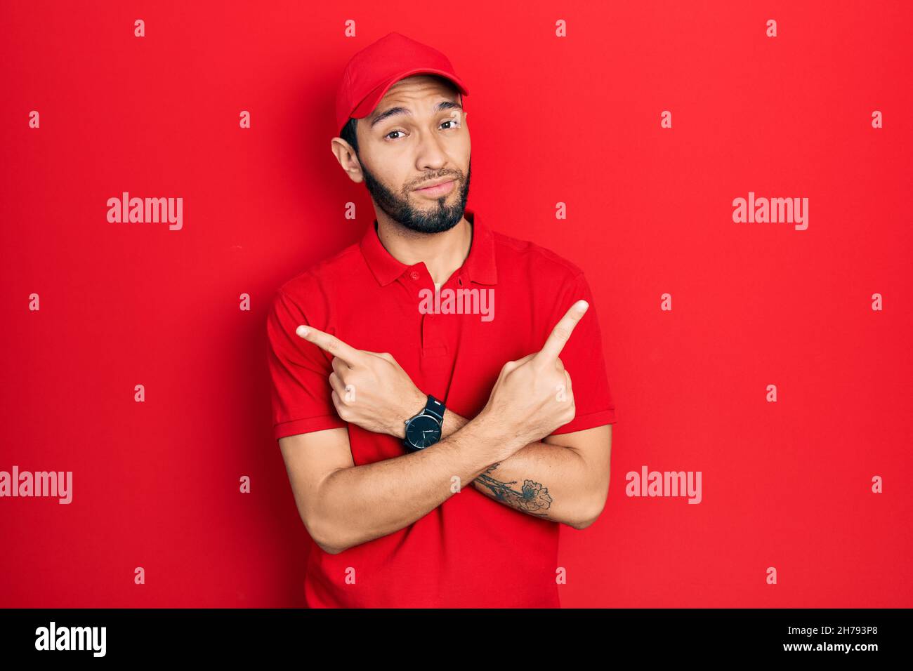 Hispanic Man With Beard Wearing Delivery Uniform And Cap Pointing To