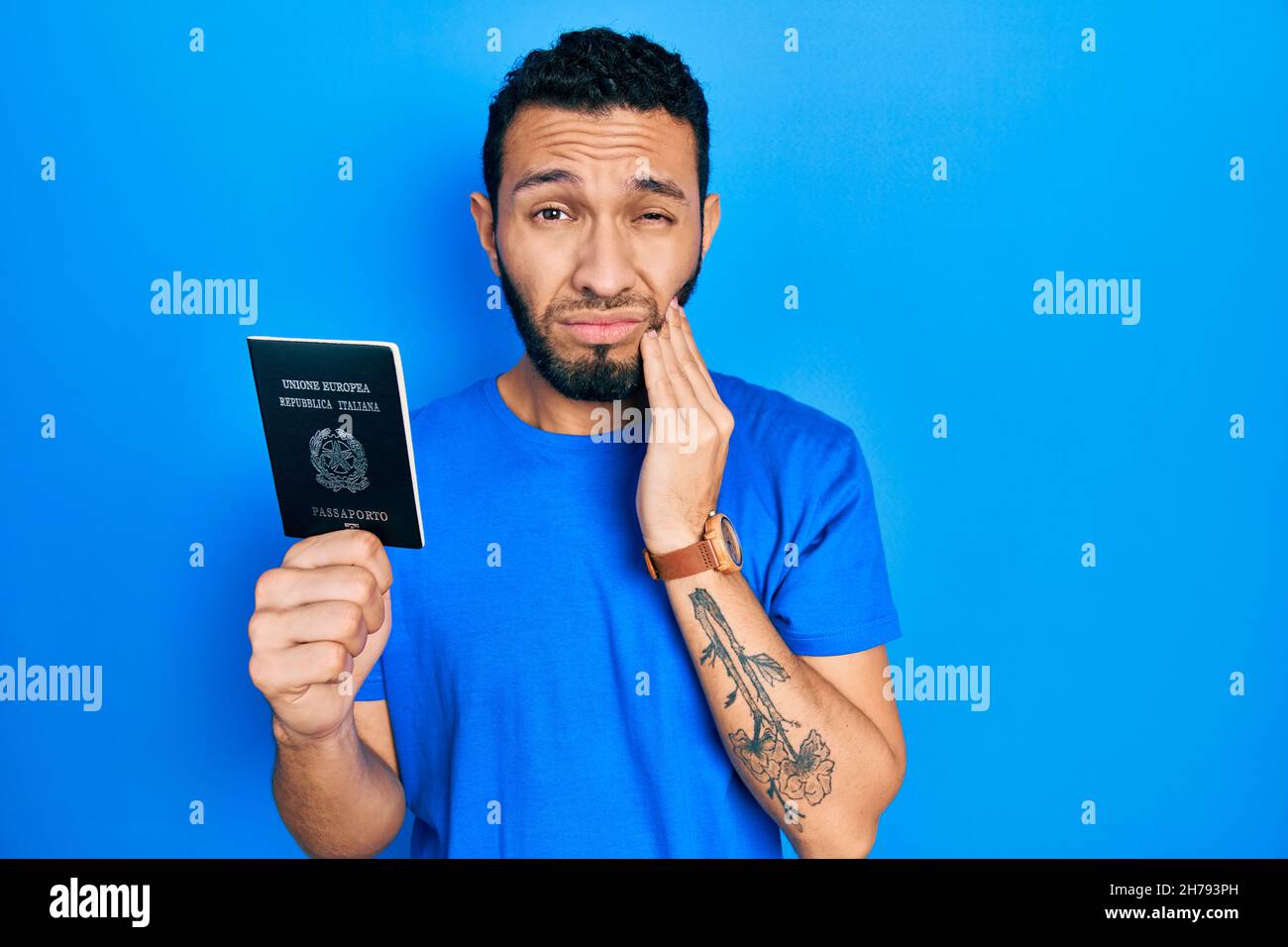 Hispanic man with beard holding italy passport touching mouth with hand ...