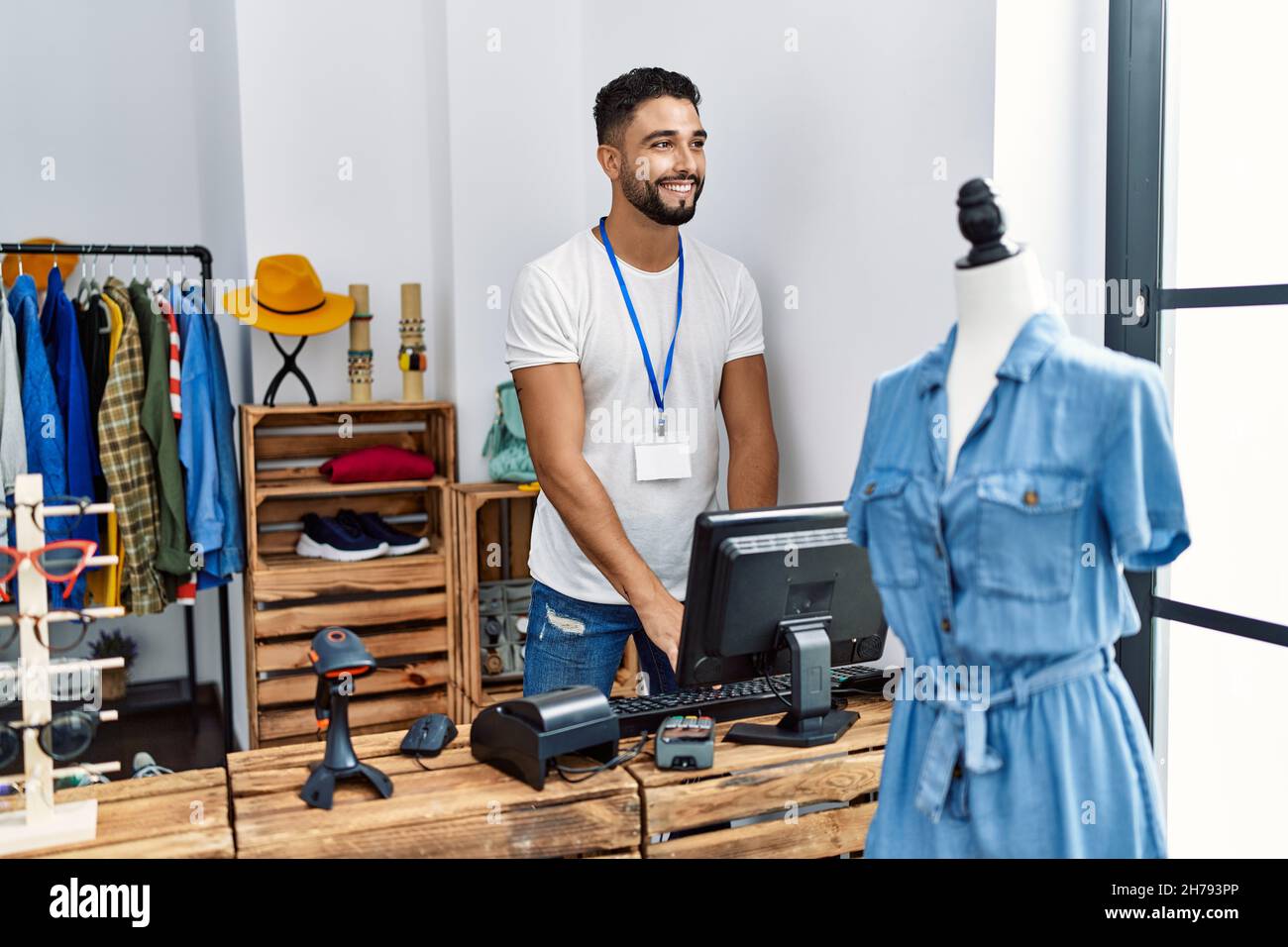 Young arab man shopkeeper smiling confident working at clothing store ...