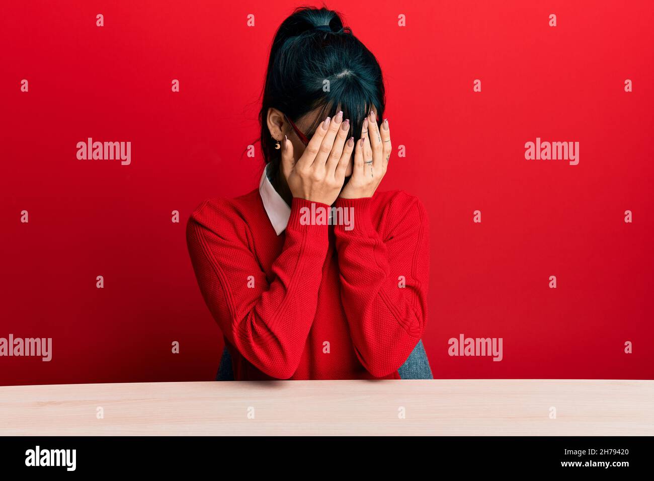 Young brunette woman with bangs wearing glasses sitting on the table ...