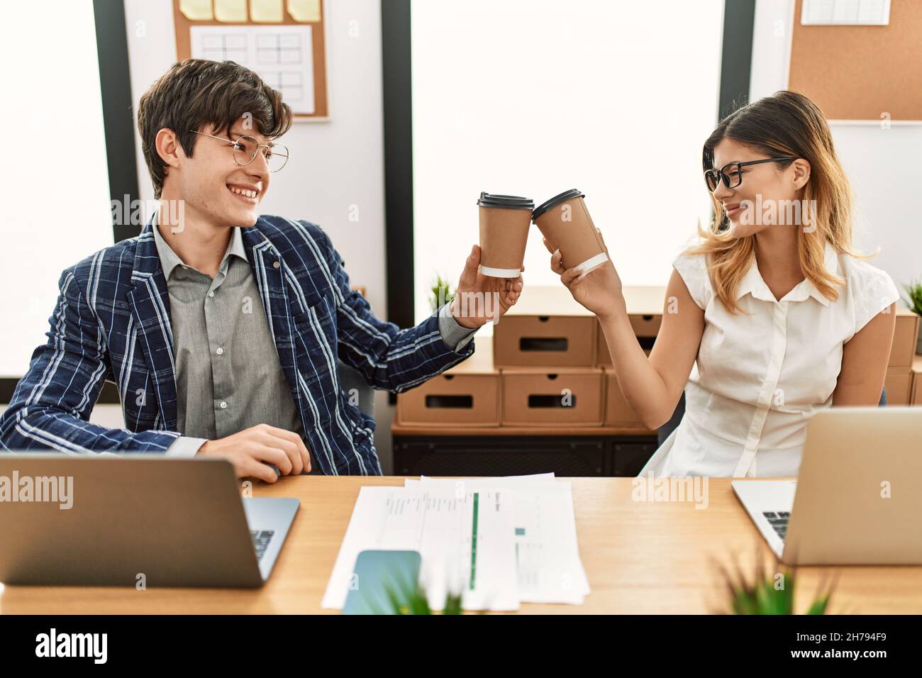 Two business workers smiling happy toasting with coffee at the office ...