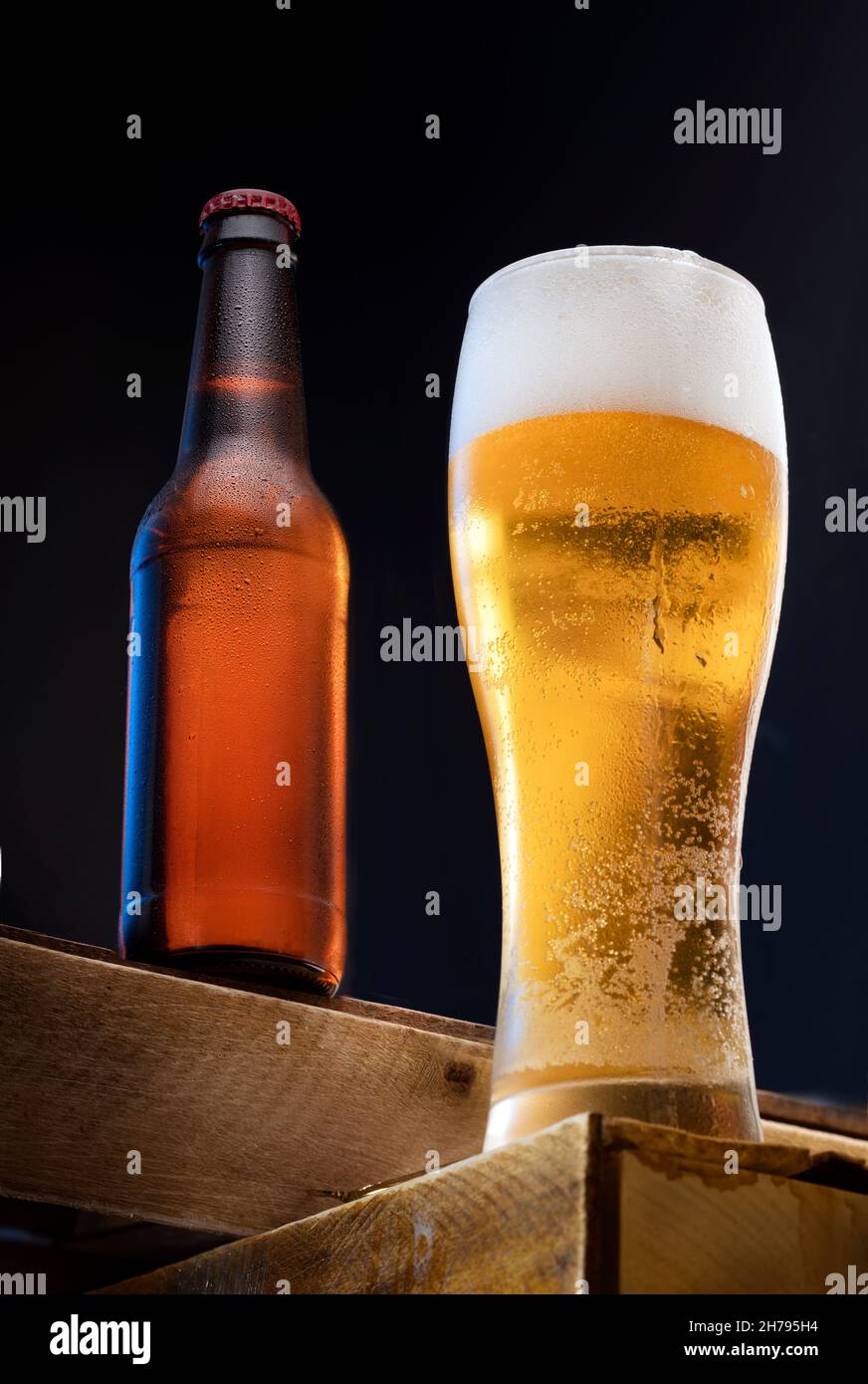 a glass of cold fresh light beer and a bottle of steamed cold beer in ...