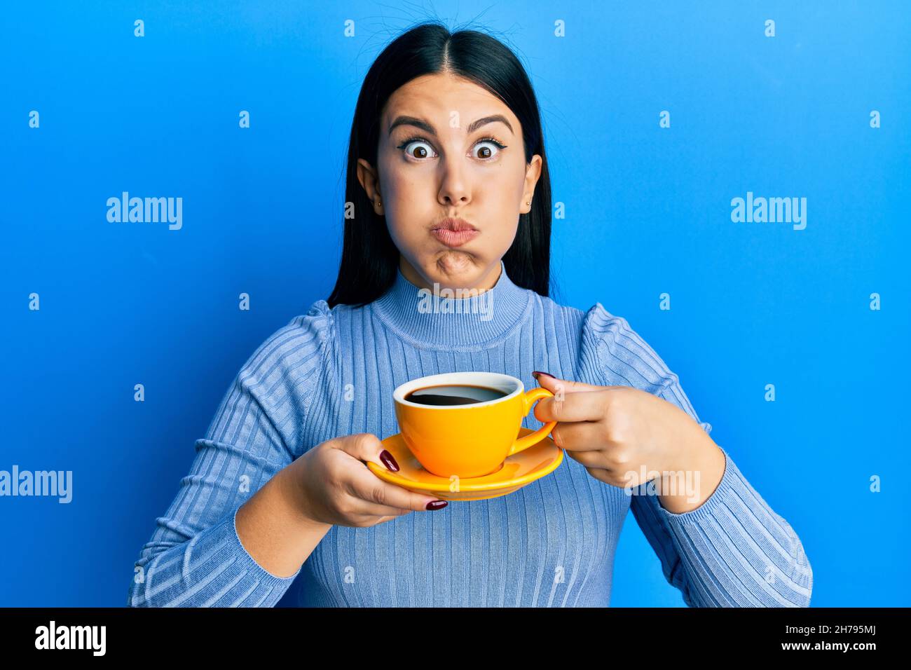 Beautiful brunette woman drinking a yellow cup of black coffee puffing ...