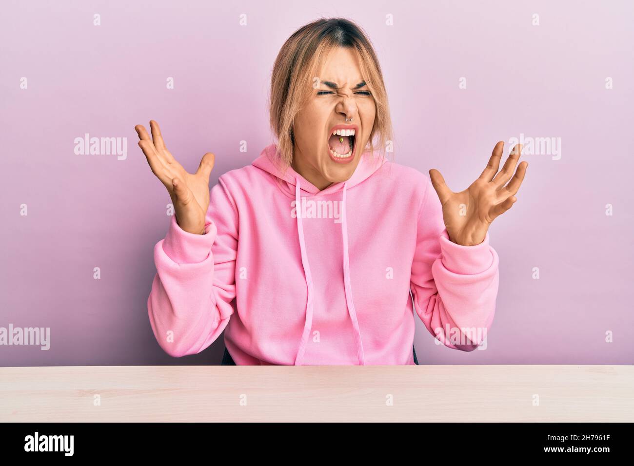 Young caucasian woman wearing casual clothes sitting on the table crazy ...