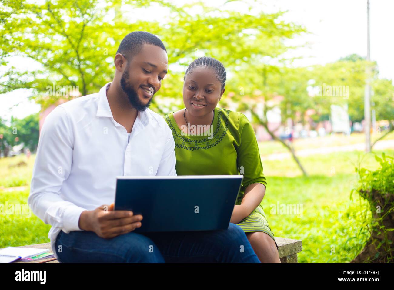 Young African male and a female watching something on a laptop with ...
