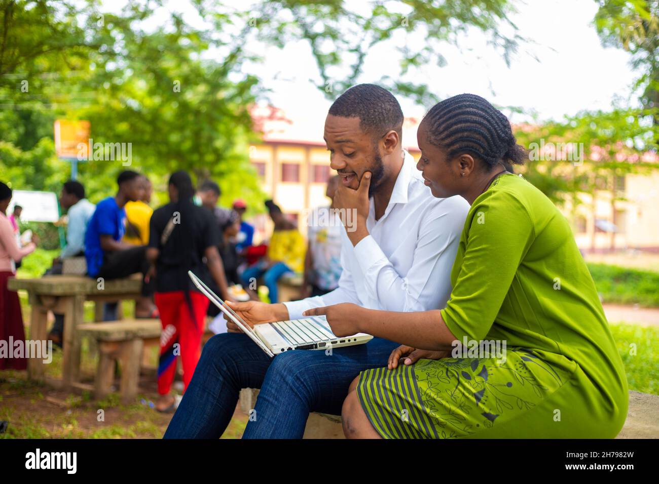 Young African male and a female watching something on a laptop with ...