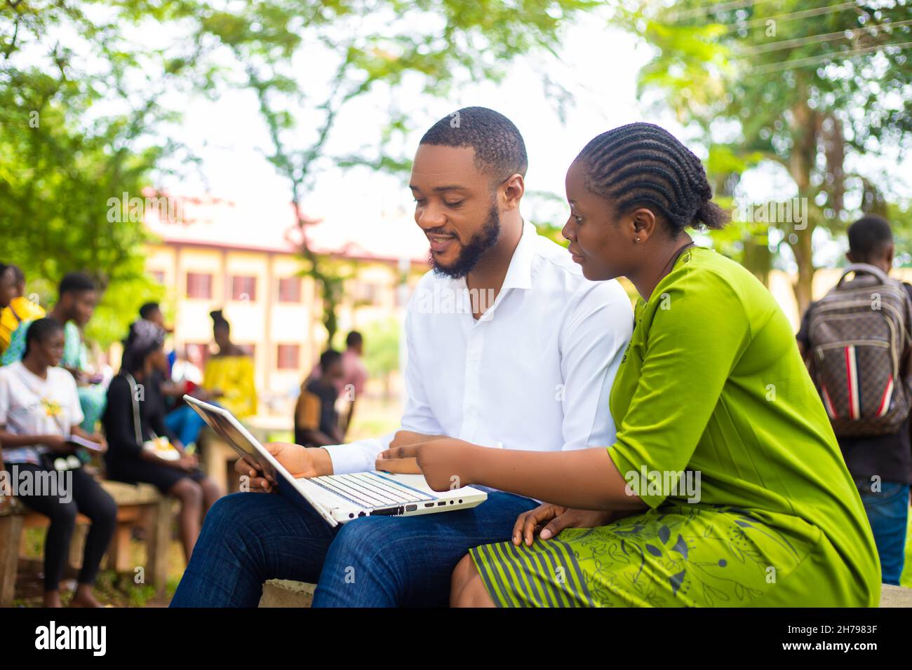 Young African male and a female watching something on a laptop with ...