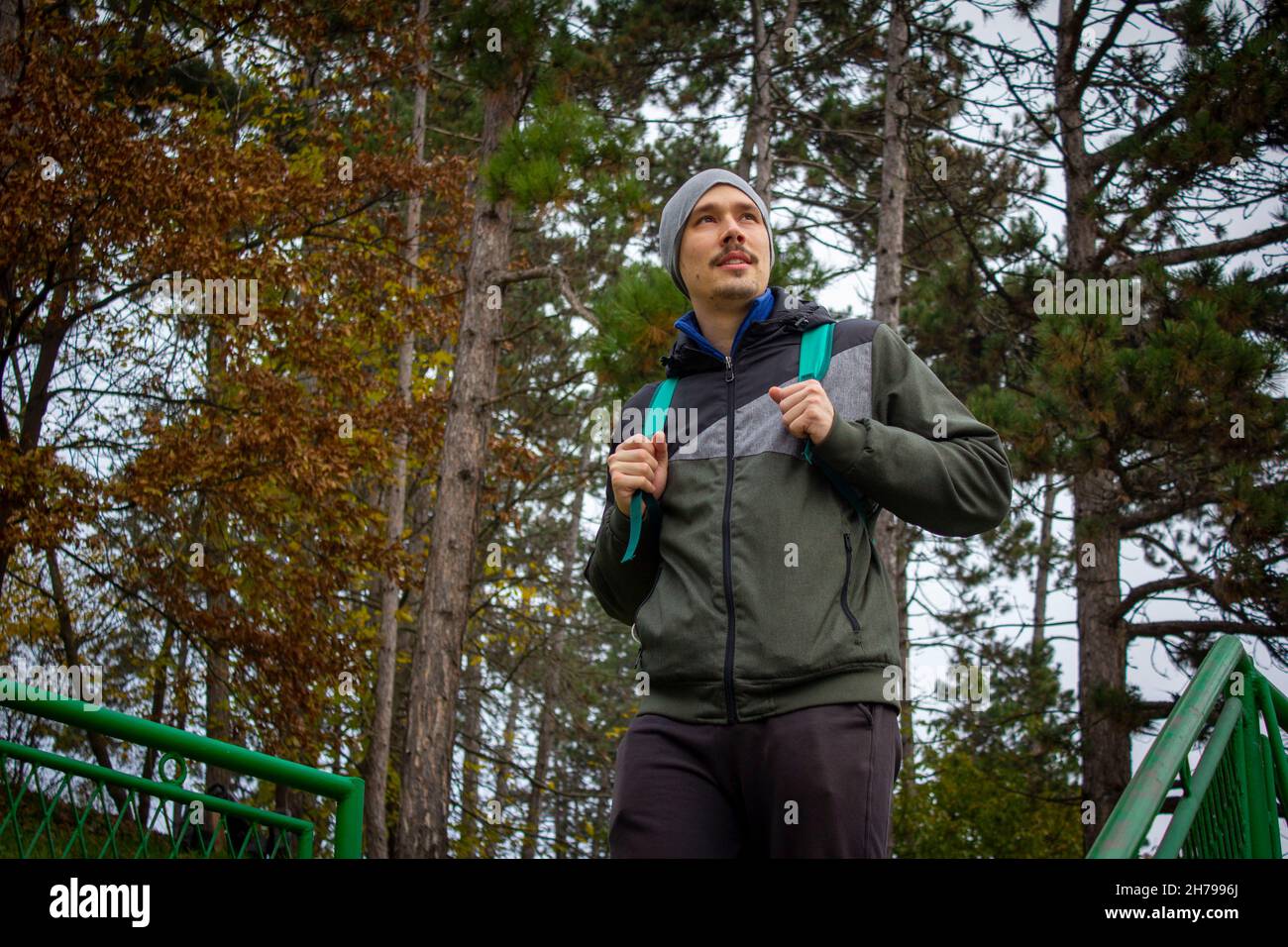 Portrait of a young smiling wanderer man with backpack goes on up the ...