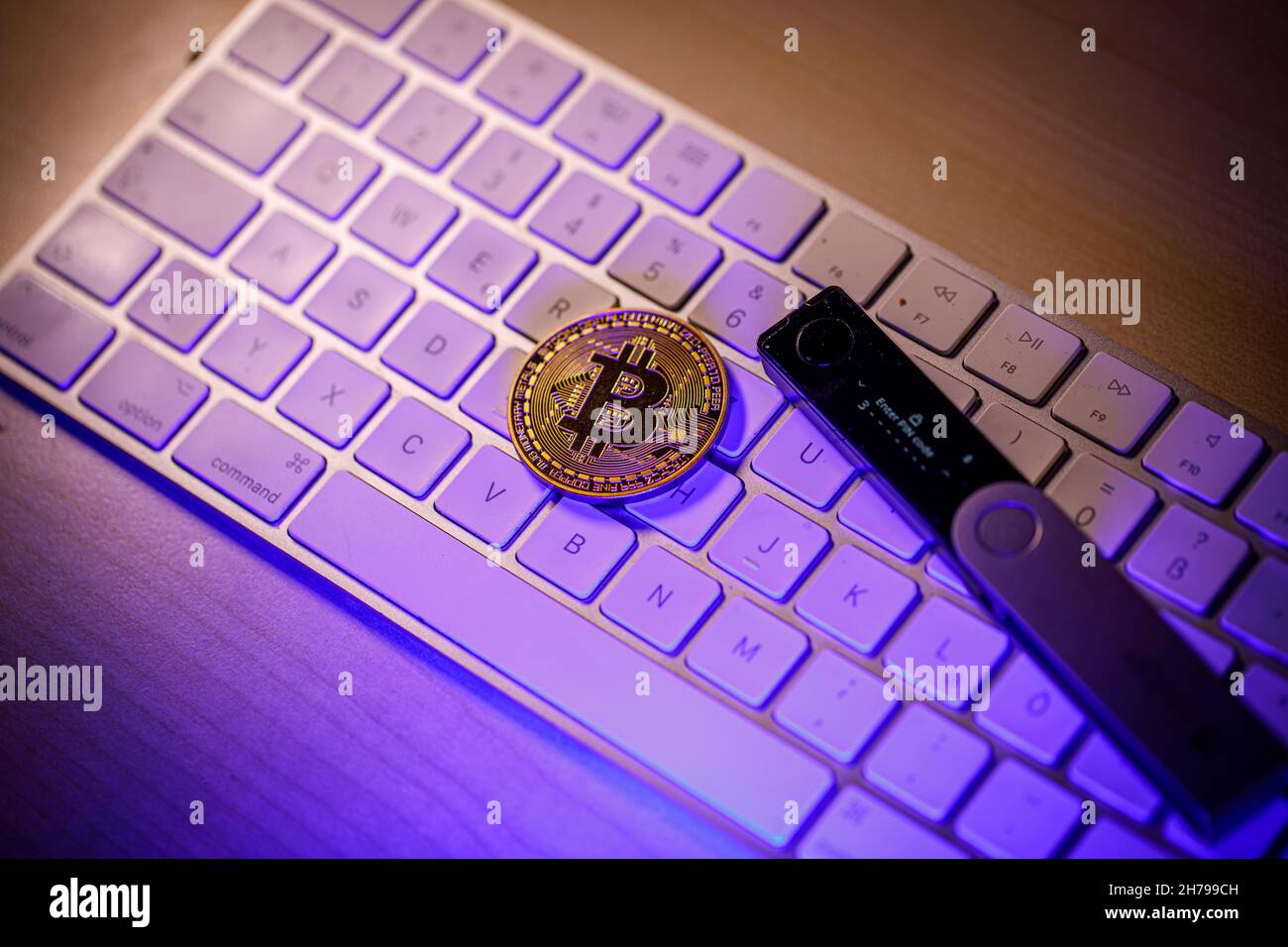 bitcoin coin lies next to a hardware wallet on a white computer ...