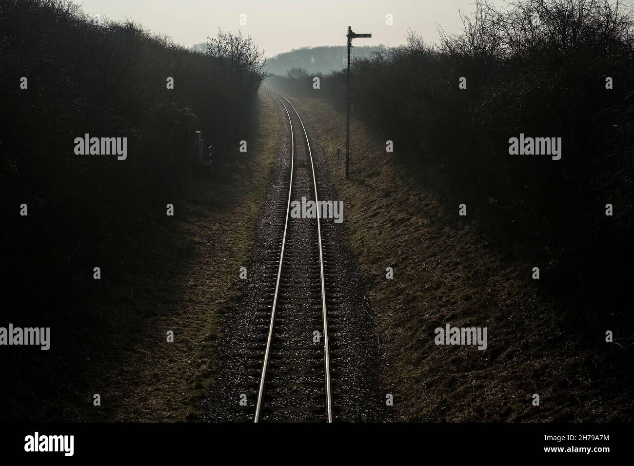 A single track railway line passing a signal and disappearing through ...