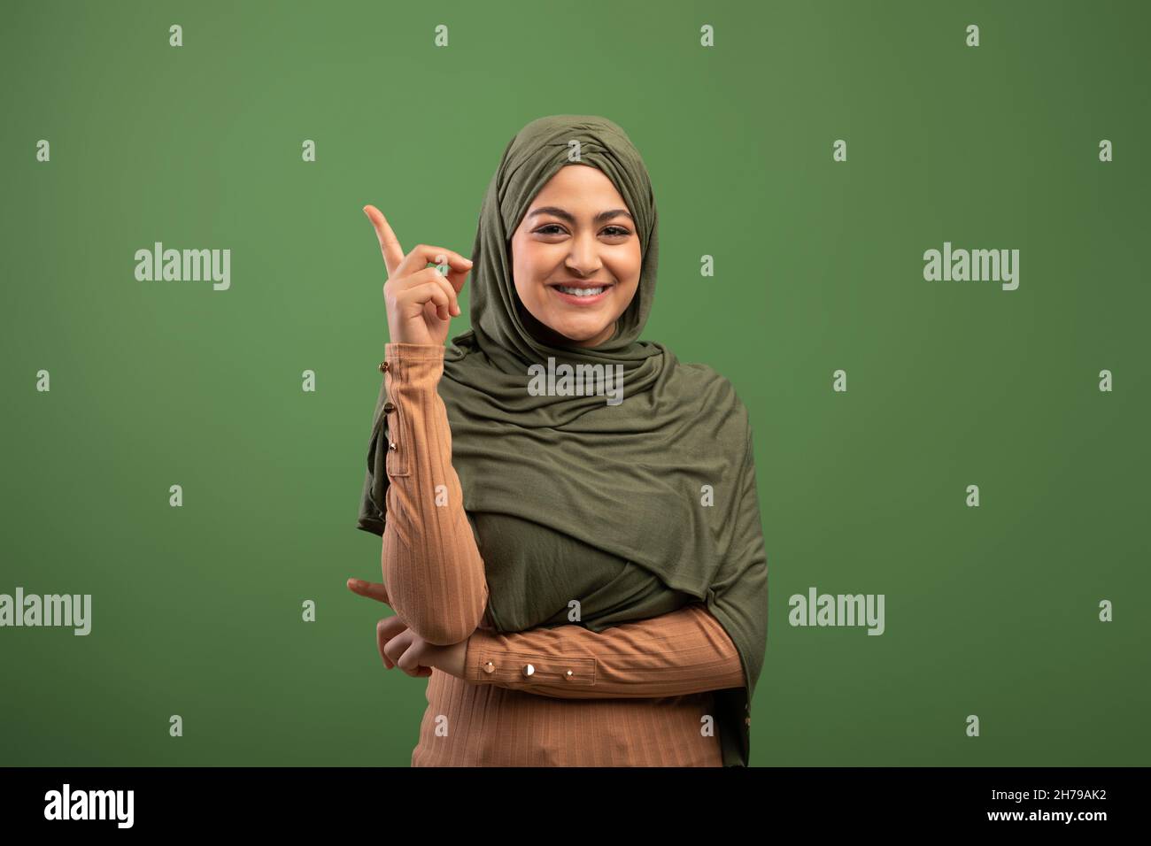 Positive islamic lady in hijab having idea, pointing finger up, having ...