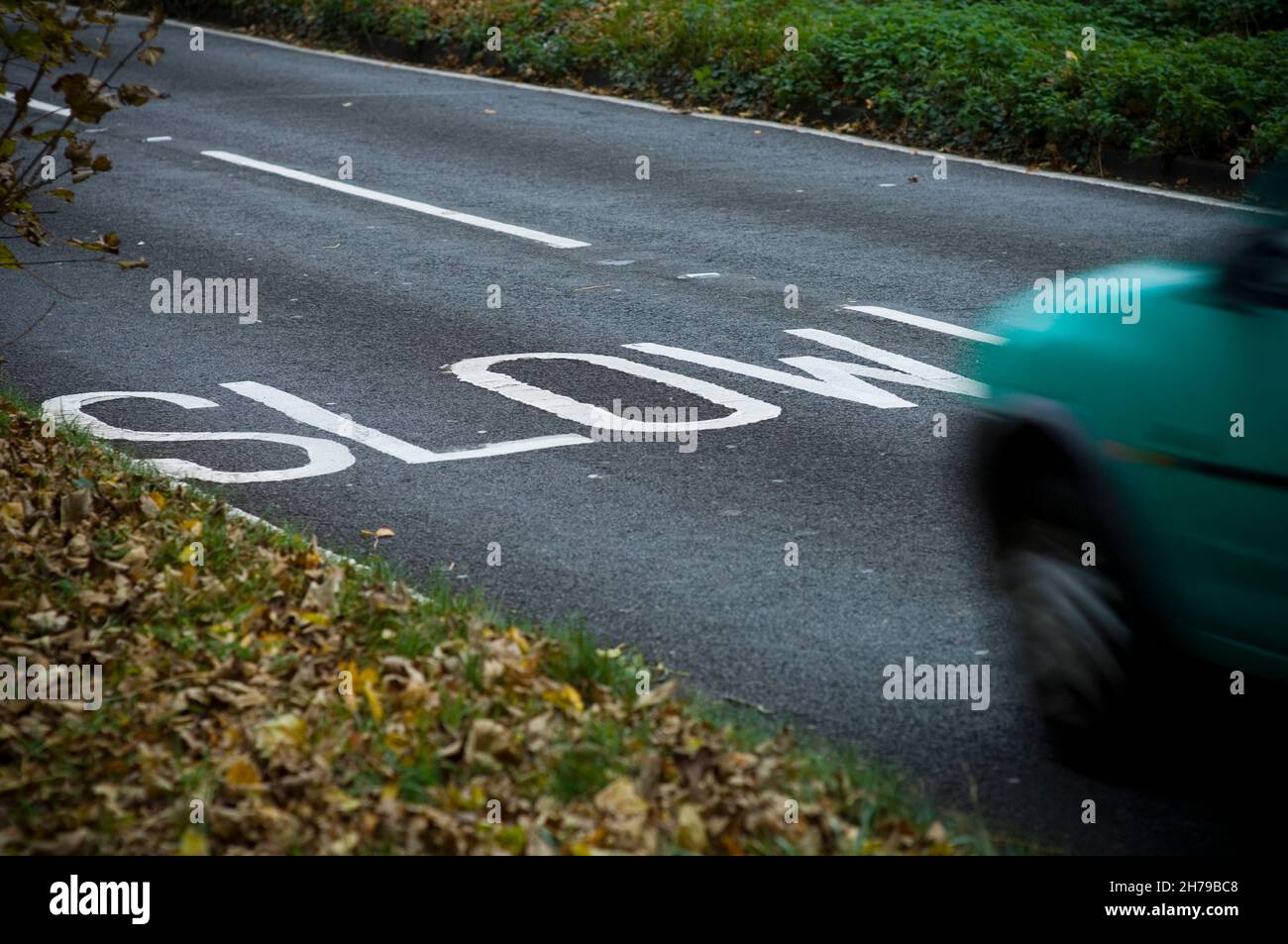 A car approaches a SLOW warning sign painted on a country road Stock ...