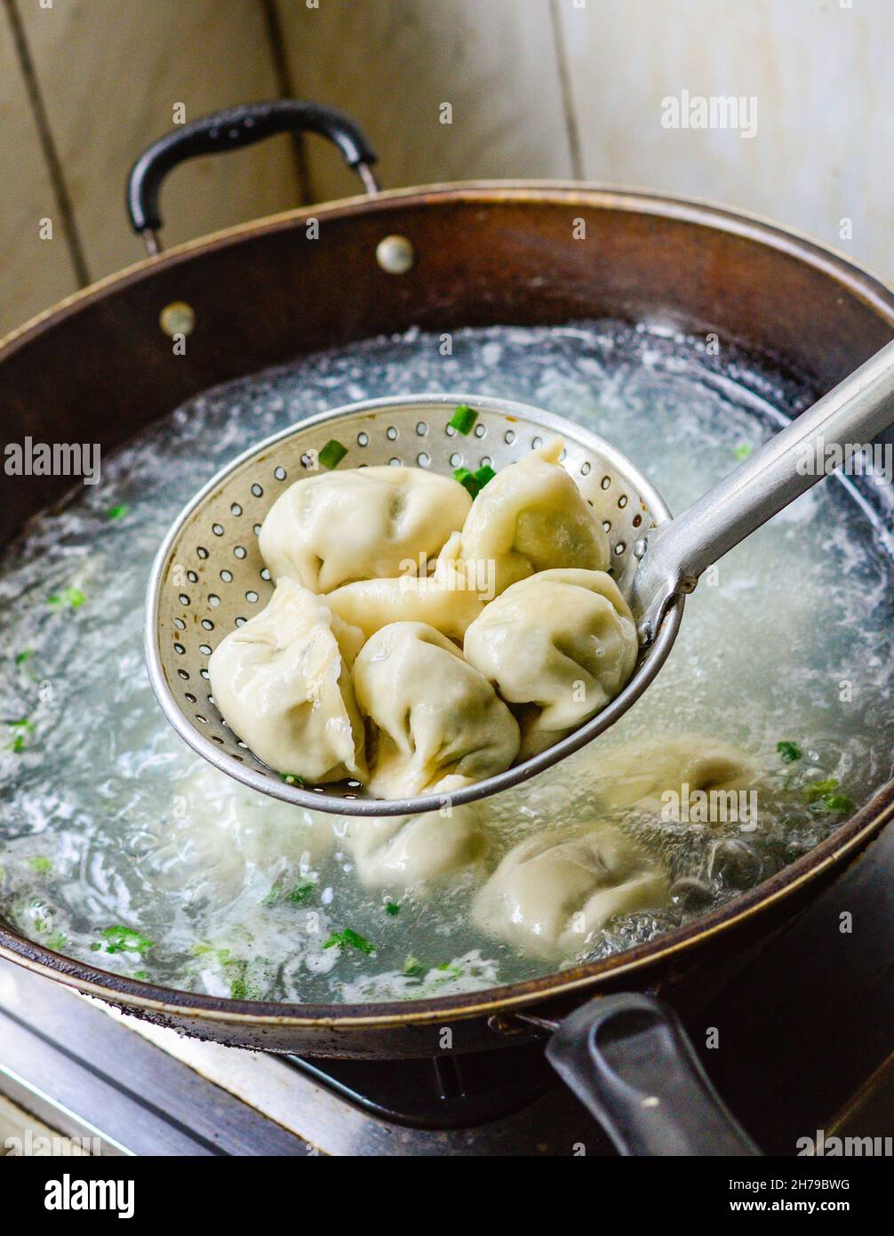 Chinese family cook dumplings and pick up the dumplings from the wok ...