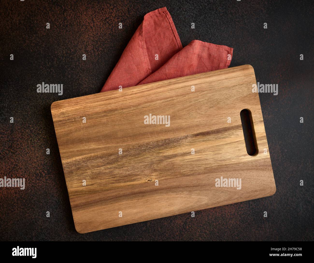 Cutting board on orange kitchen linen towel on dark kitchen table. Top ...