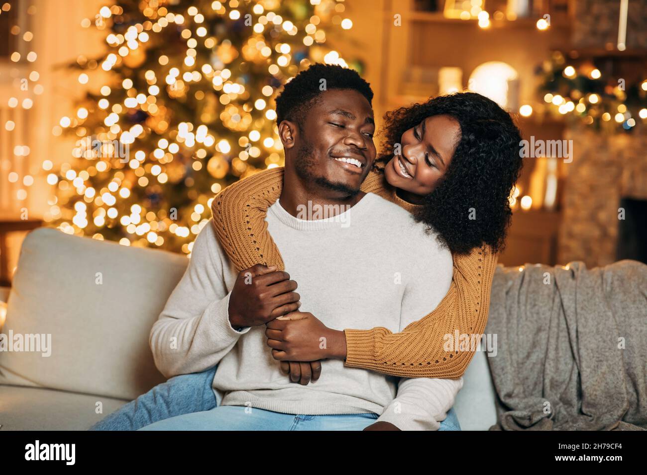 Affectionate young black couple hugging on sofa in decorated room with ...