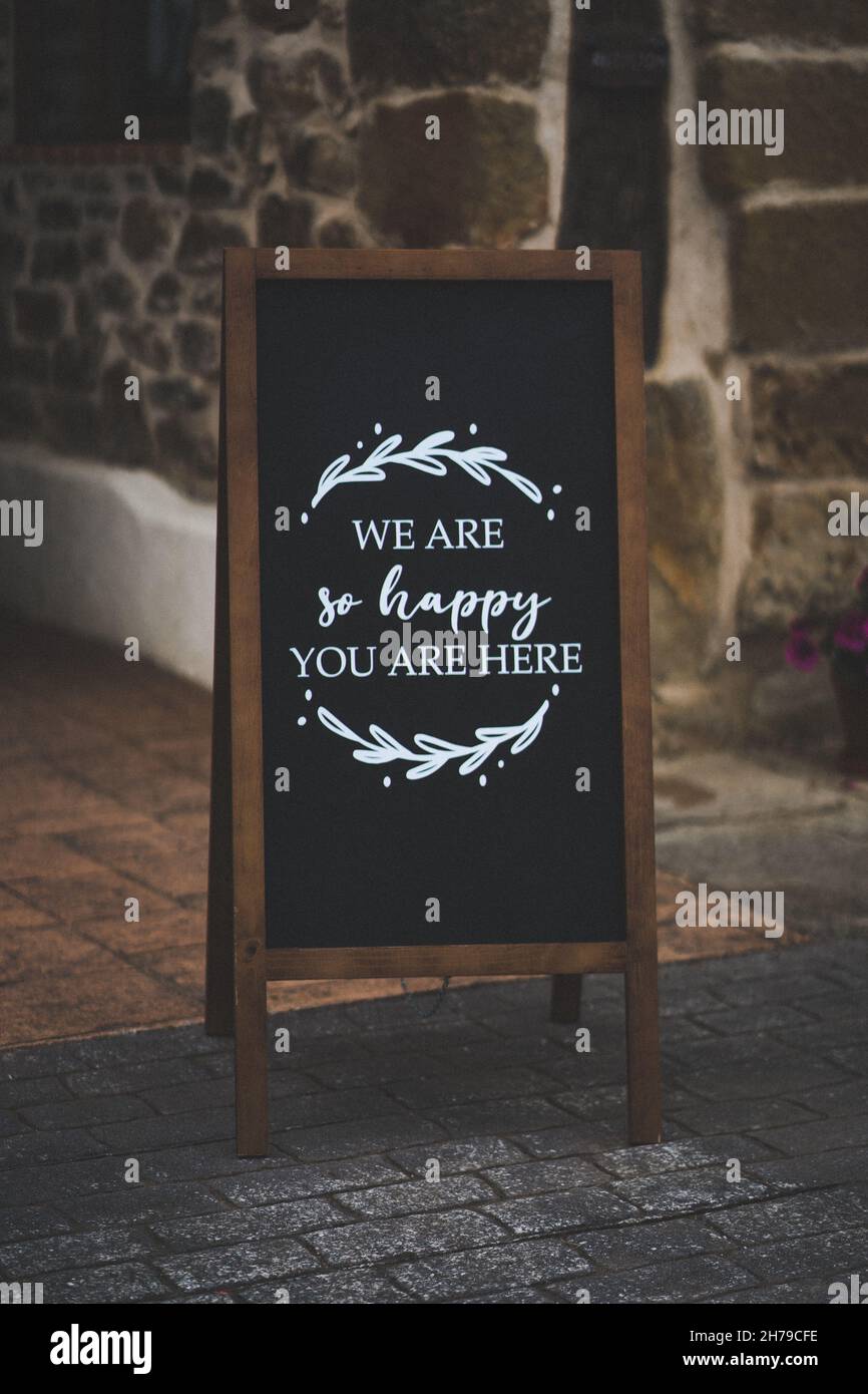 A sign saying 'we are so happy you are here' in front of a cafe Stock ...