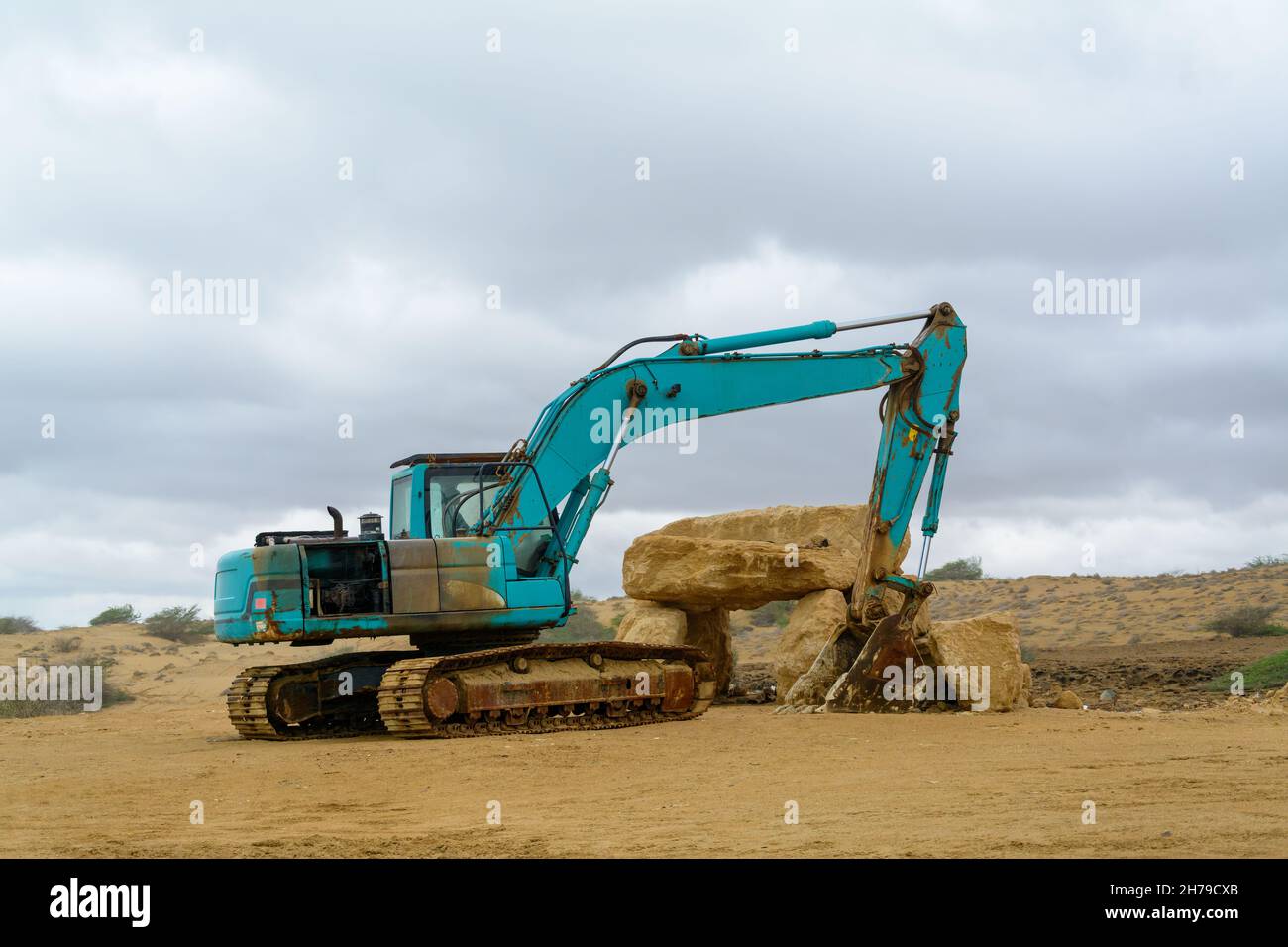 back side view of industrial rusty blue excavator parked in the beach ...