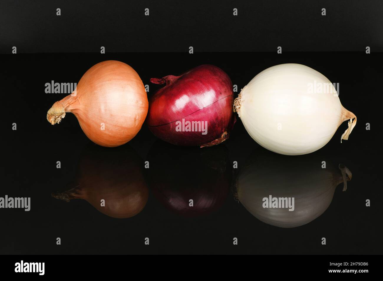 Three onion bulbs of different colors (red, yellow and white) isolated ...