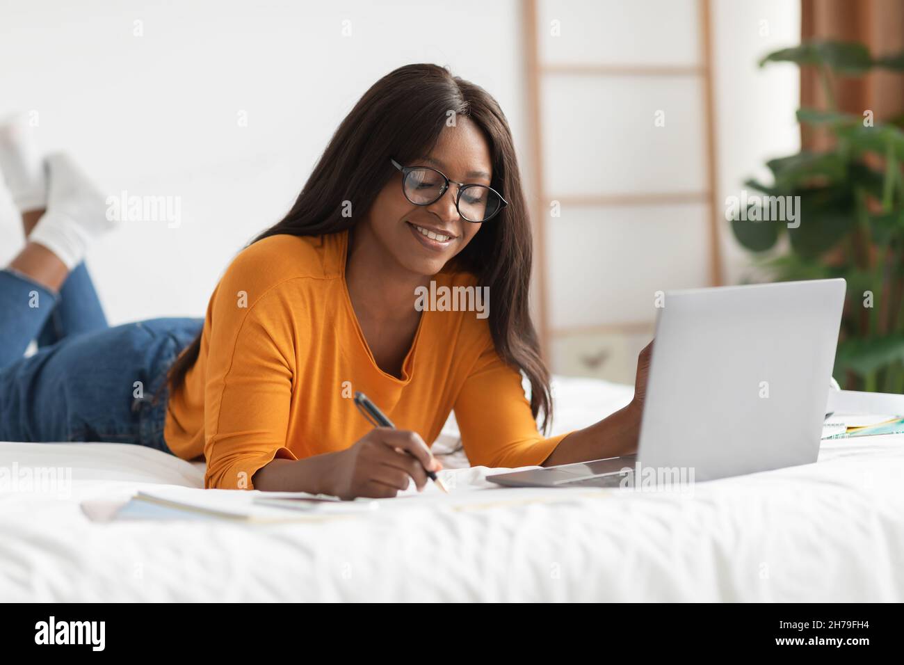 Black Woman Learning Taking Notes Lying With Laptop In Bedroom Stock ...