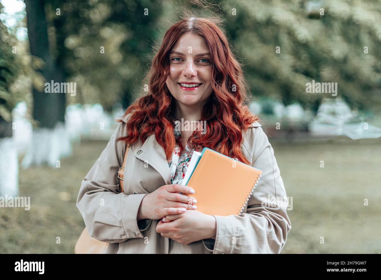 Young caucasian female student with books outside near campus in nature ...