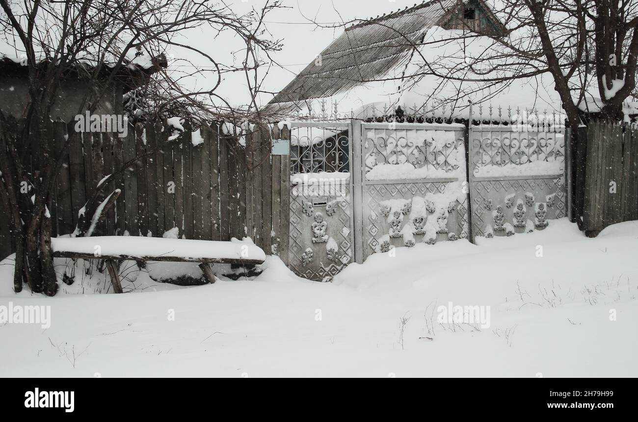 Snow covered gate in the poor village Stock Photo - Alamy