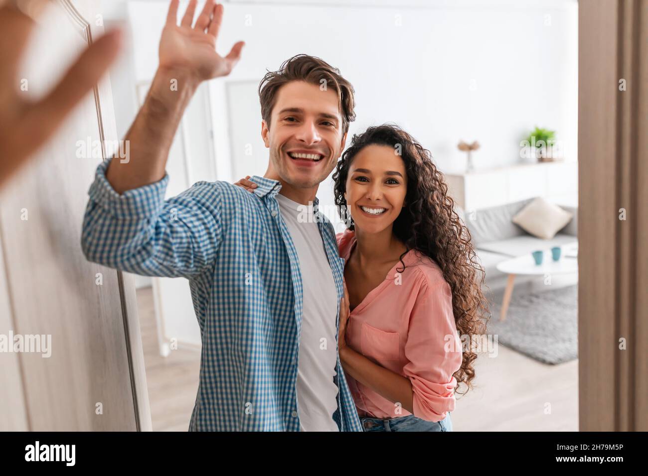 Happy couple inviting people to enter home, giving high five Stock ...