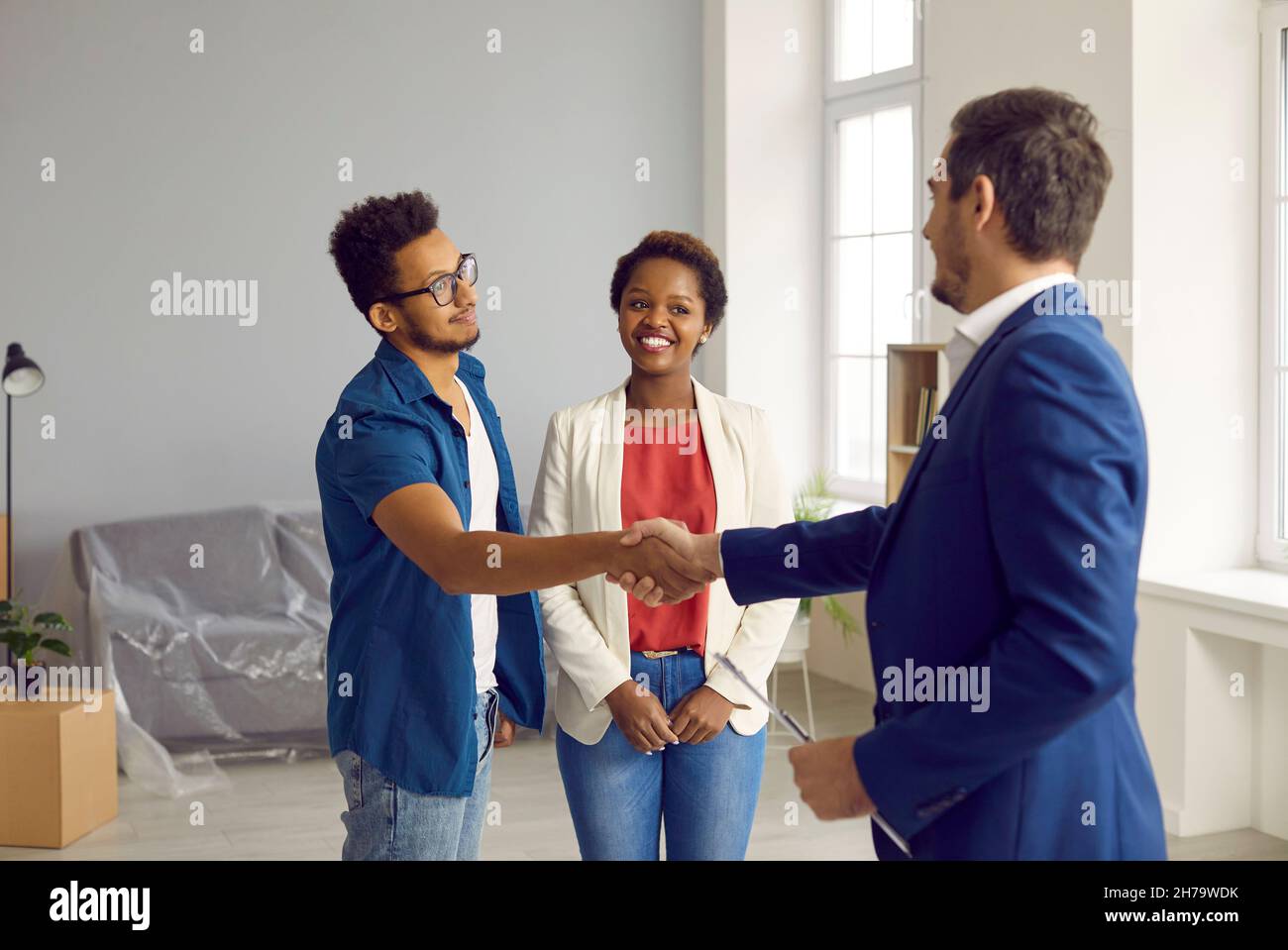 Happy young married couple buys house and closes deal with realtor with ...