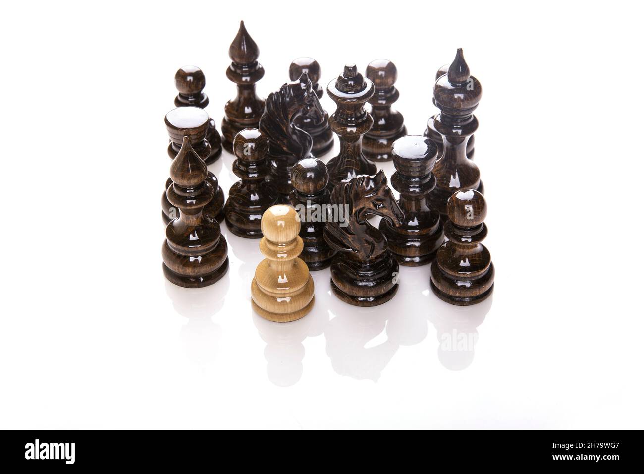 A single pawn against black chess pieces isolated on white background ...