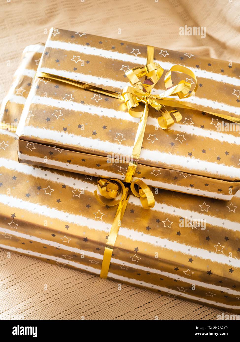 Christmas stack of golden wrapped gift boxes on beige plaid Stock Photo ...