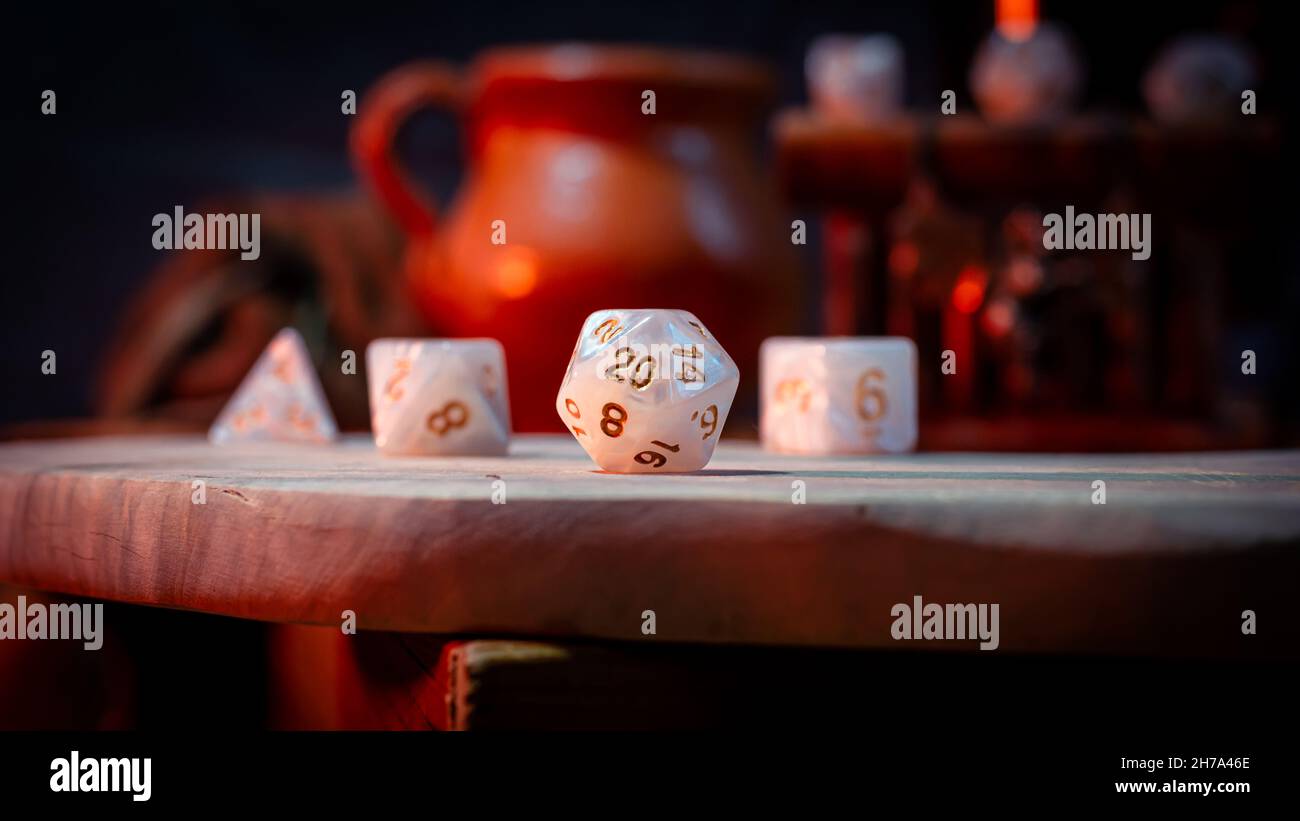 A close-up image of a pearly white 20-sided die with golden numbers on ...