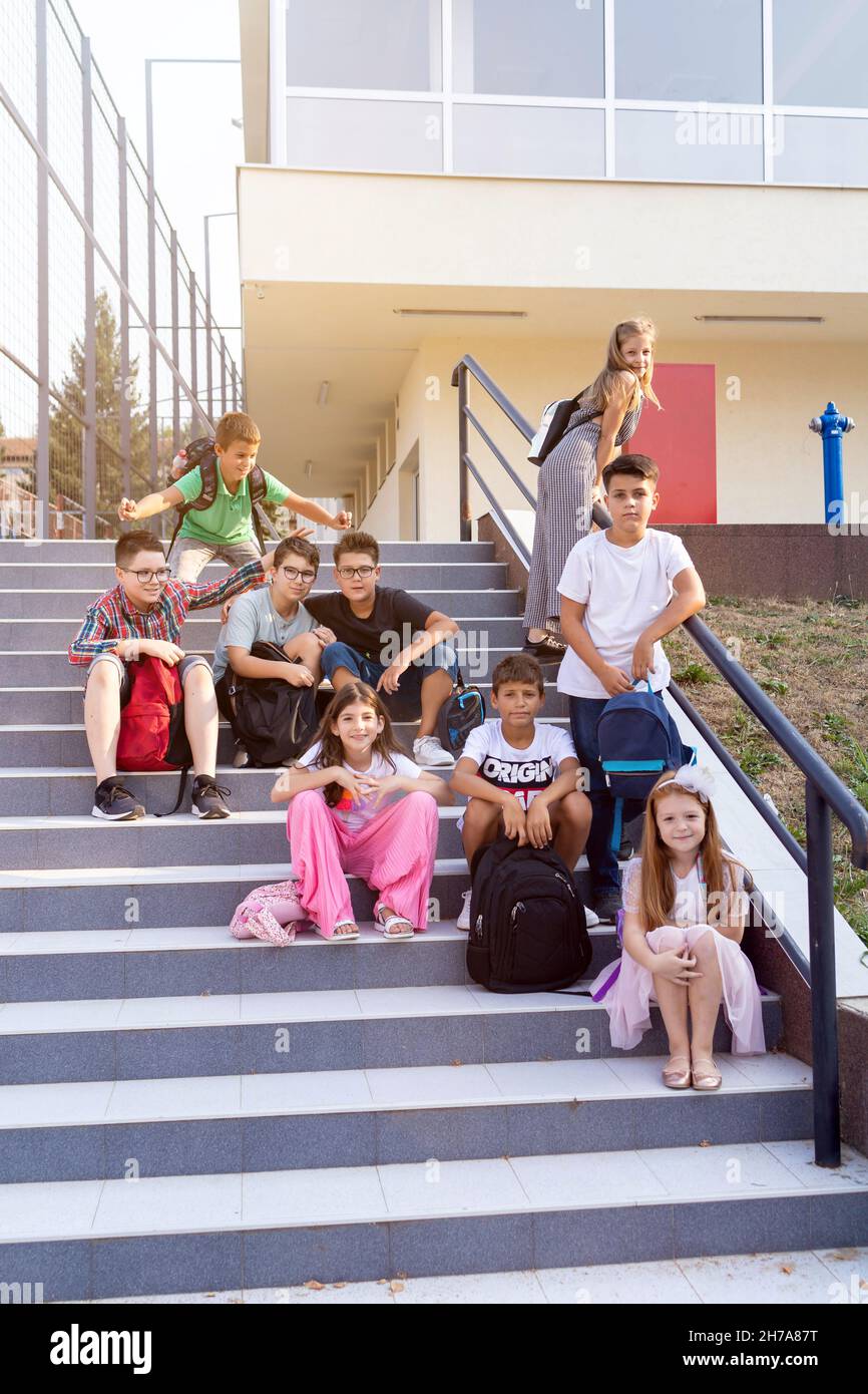 Group of elementary school kids having fun before classes, sitting on ...