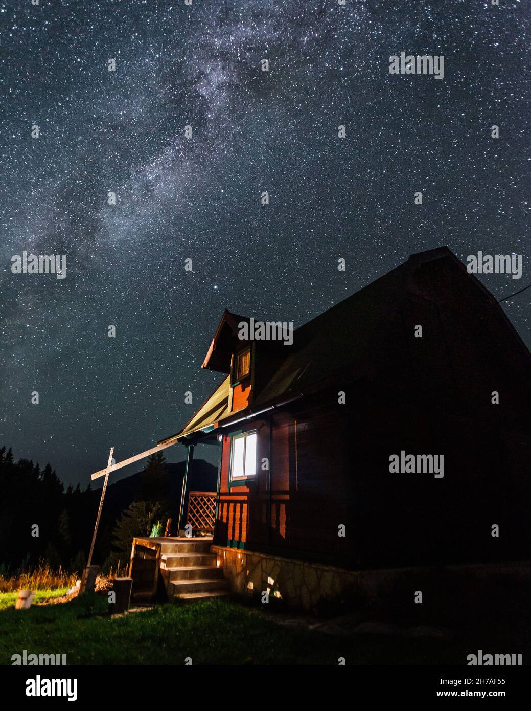 A small house in a forest under a glowing starry sky at night Stock ...