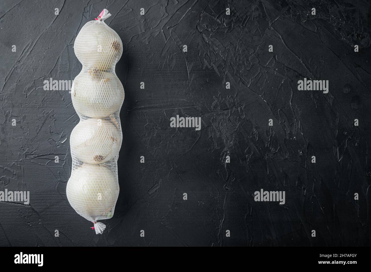 White onions in a grid, on black background, top view flat lay with ...