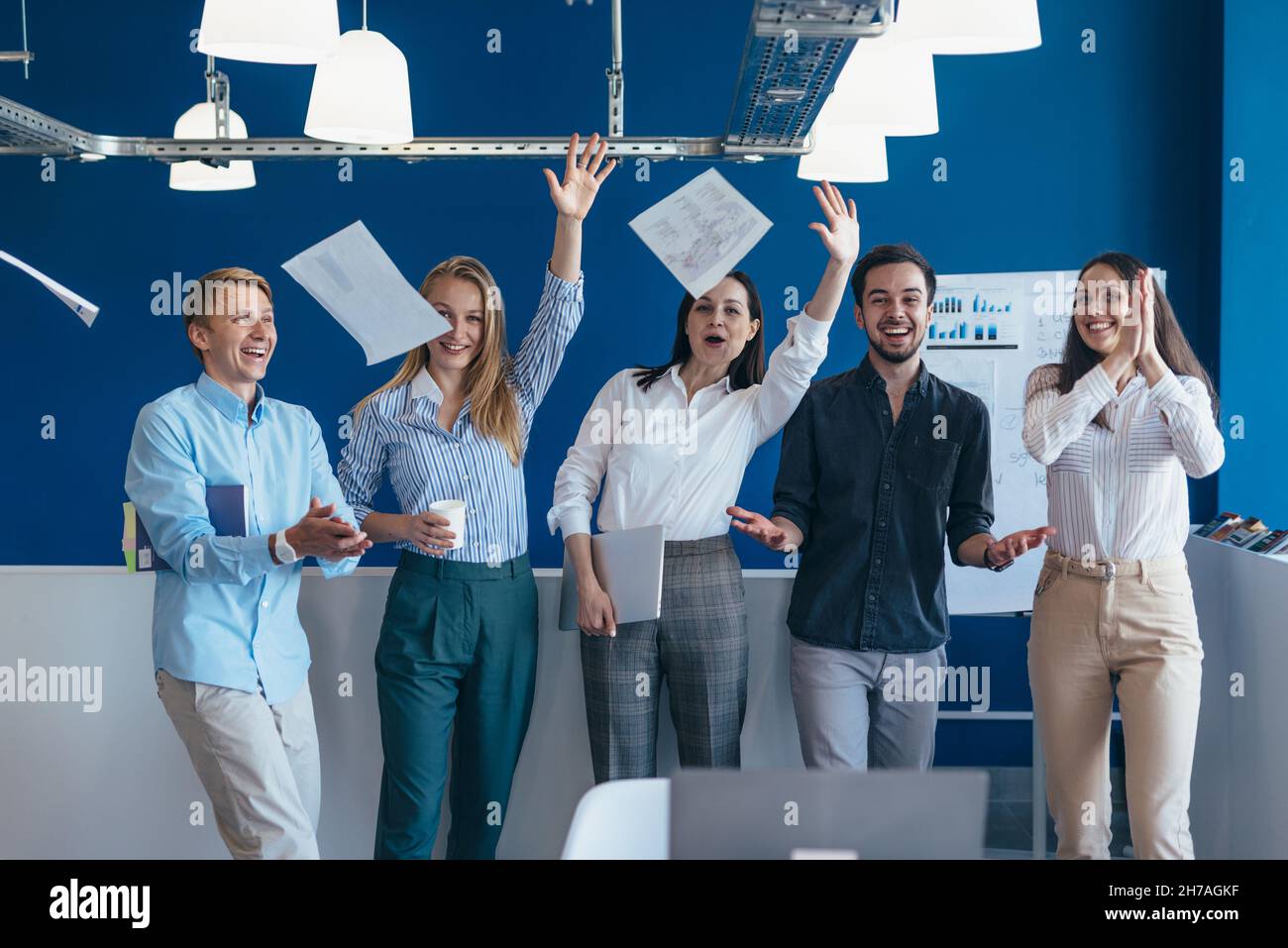 Group of joyful young people tossing papers, waving their hands Stock ...