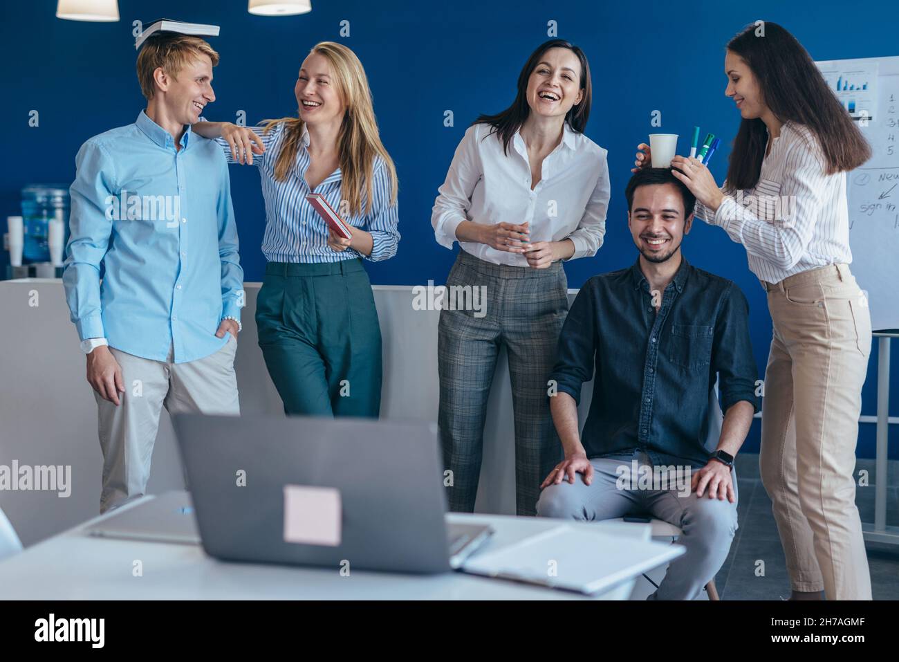 Group of young people standing in class during recess and laughing ...