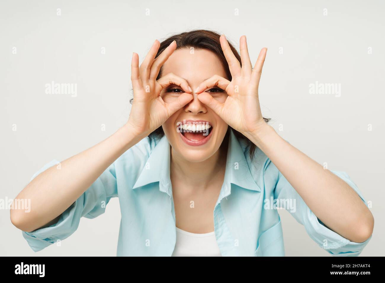 Portrait of a smiling woman showing a OK sign and looking into a camera ...