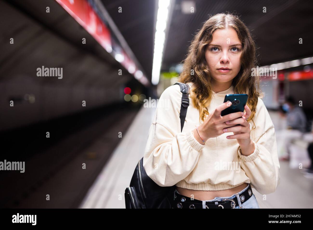 Thoughtful girl, walking along the platform of a subway station, holds ...