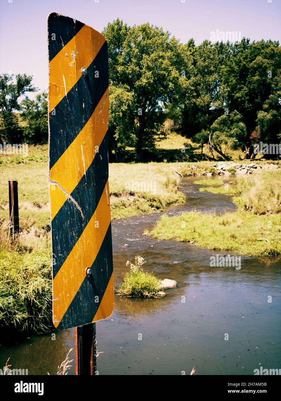 A vertical caution sign in front of a swamp Stock Photo - Alamy
